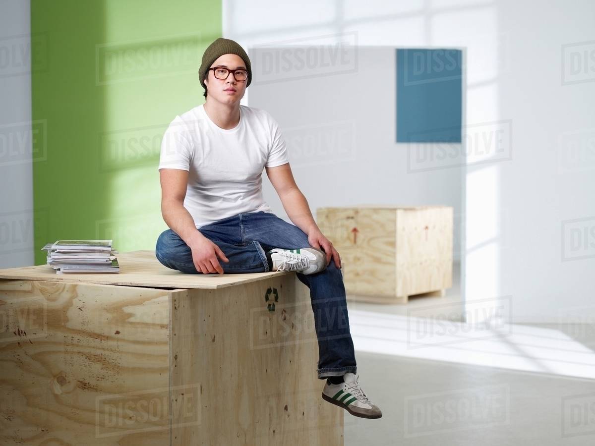 Young man sitting on box - Royalty-free Stock Photo | Dissolve