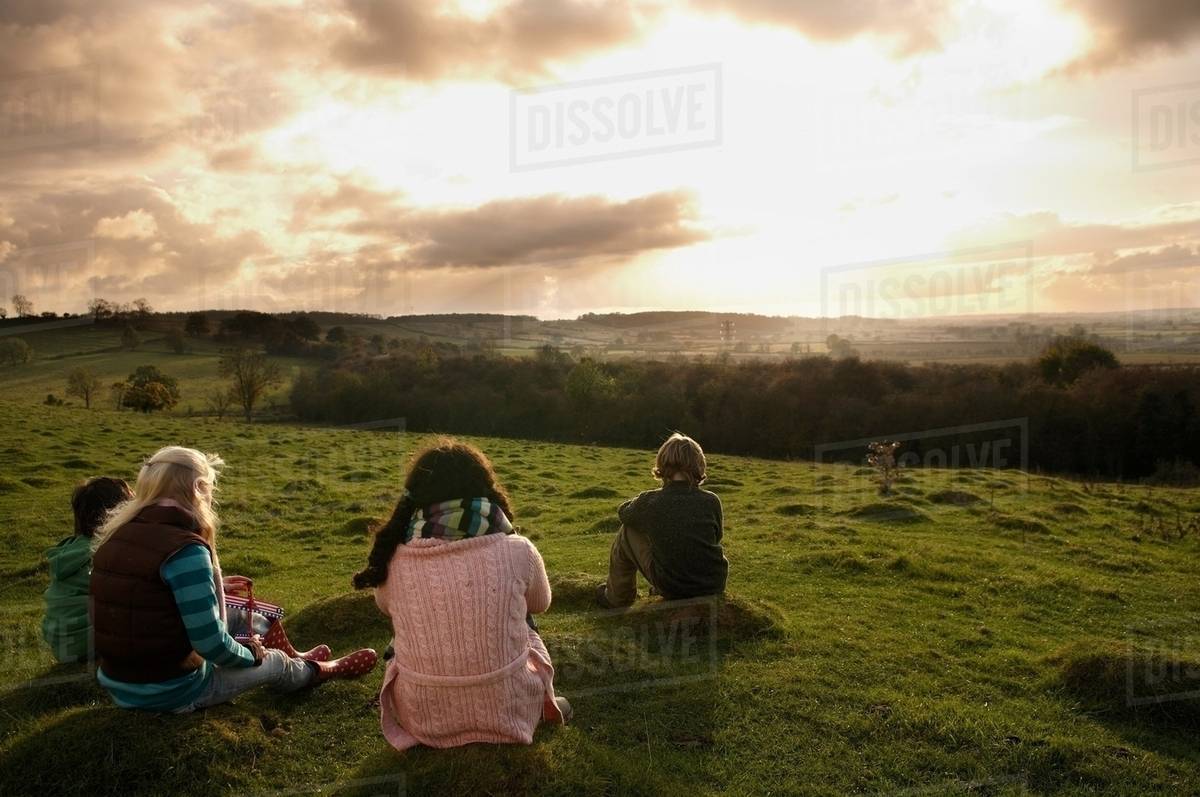 Children watching sunset on hill - Royalty-free Stock Photo | Dissolve