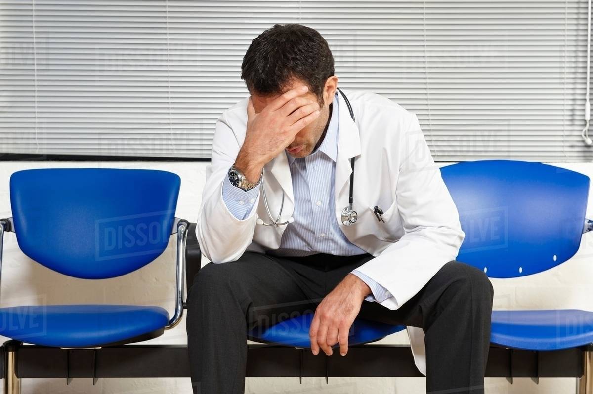 Doctor with head in his hands - Royalty-free Stock Photo | Dissolve