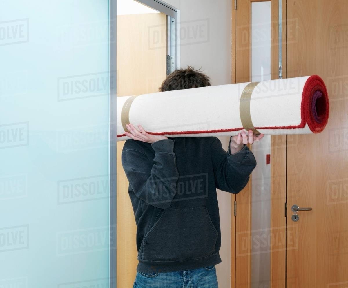 Man carrying rolled rug - Stock Photo - Dissolve