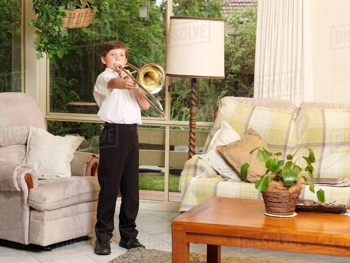Boy playing trombone in sitting room - Stock Photo - Dissolve
