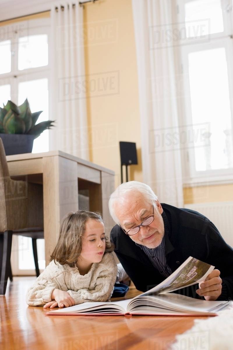 Old man reading book to young girl - Royalty-free Stock Photo | Dissolve