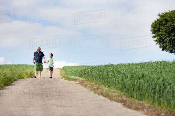 Father and son walking down a road - Stock Photo - Dissolve