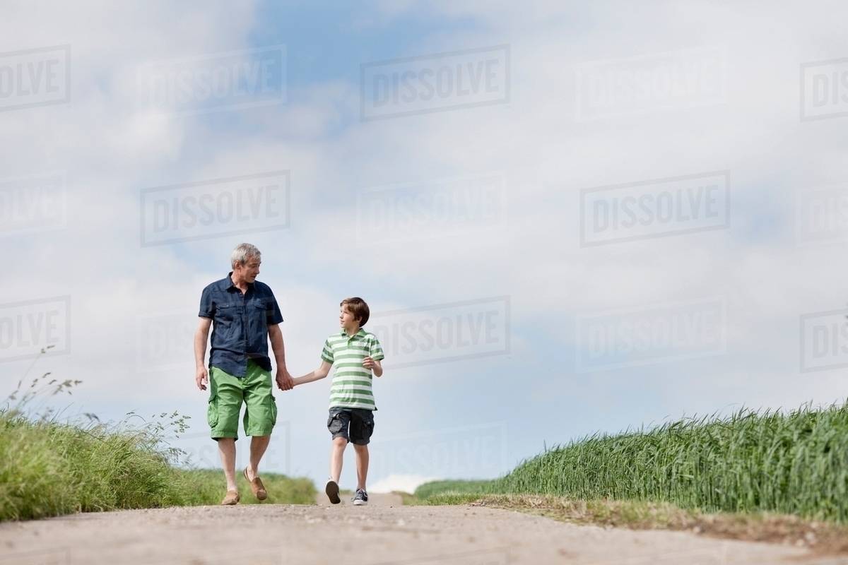 Father and son walking down a road - Stock Photo - Dissolve