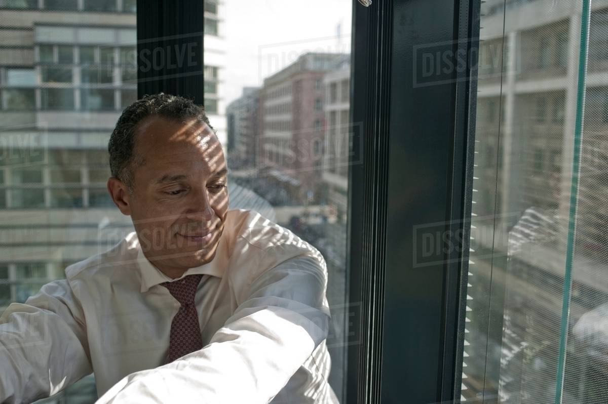 Man leaning at window smiling - Stock Photo - Dissolve