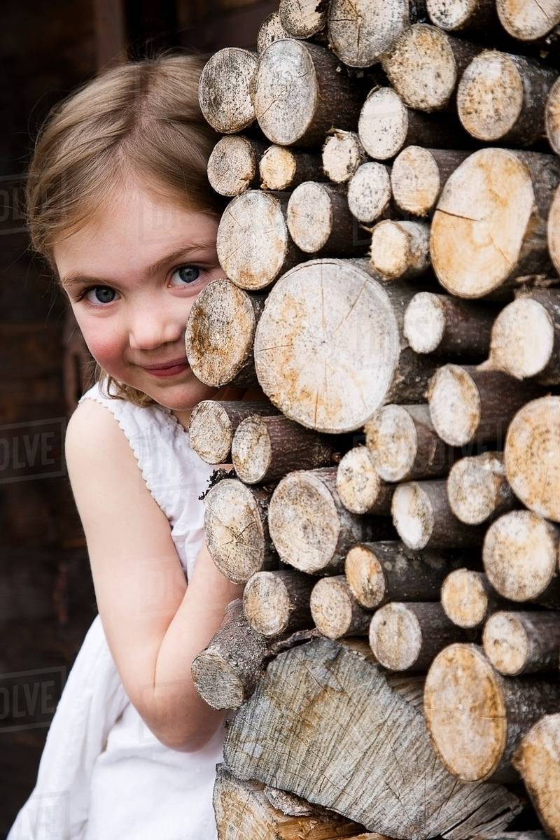 Girl hiding behind logs. - Royalty-free Stock Photo | Dissolve