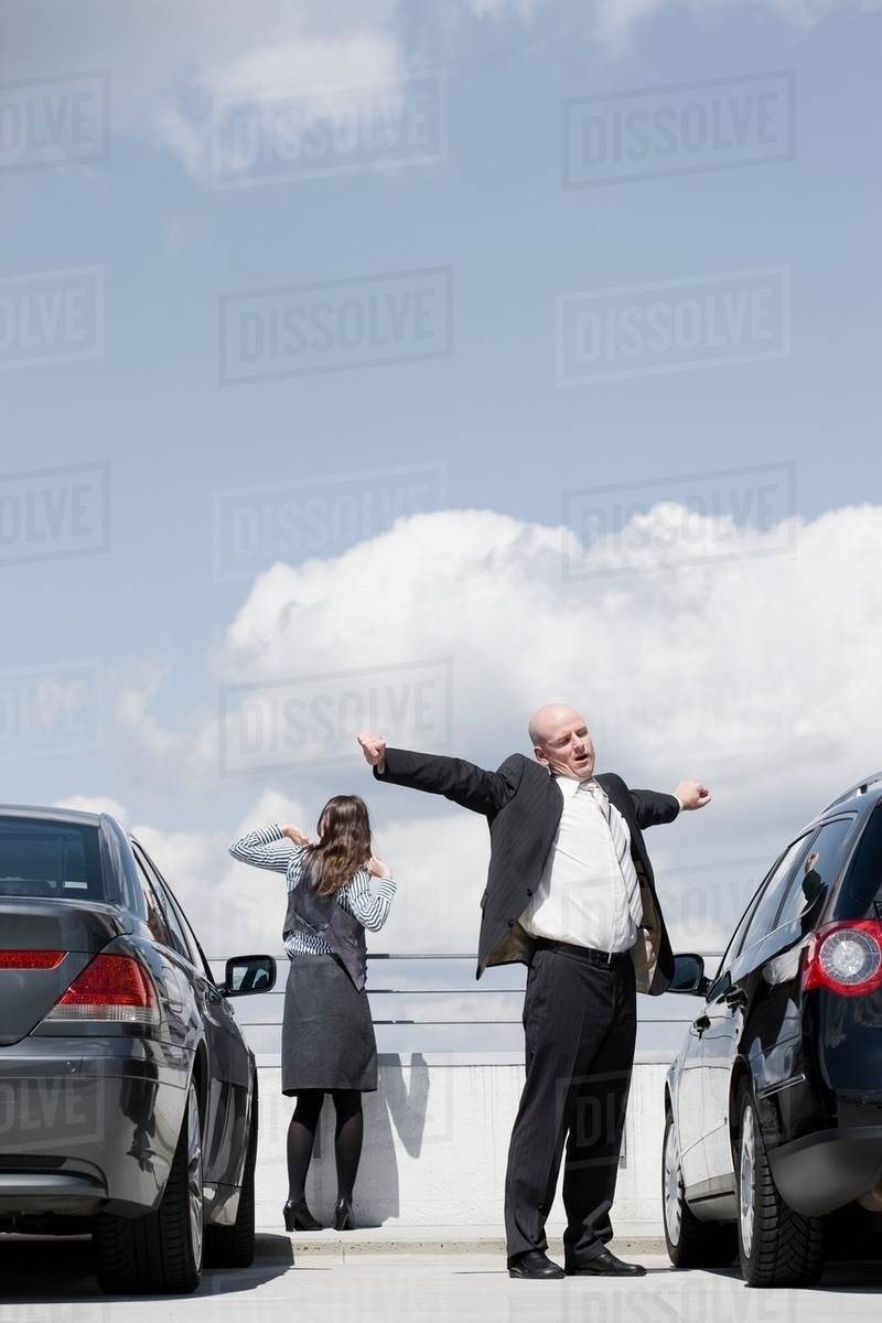 Man and woman stretching between cars - Royalty-free Stock Photo | Dissolve
