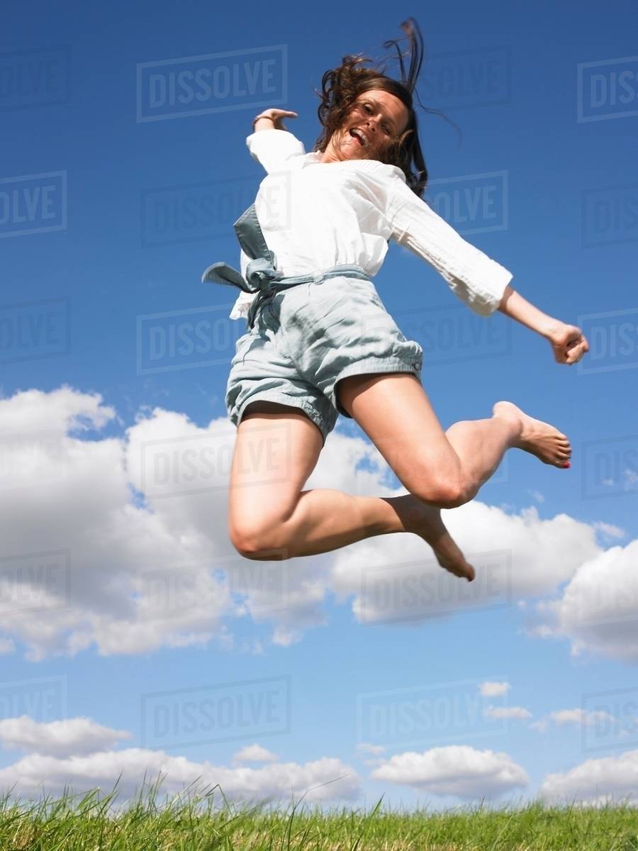 Young woman jumping - Stock Photo - Dissolve