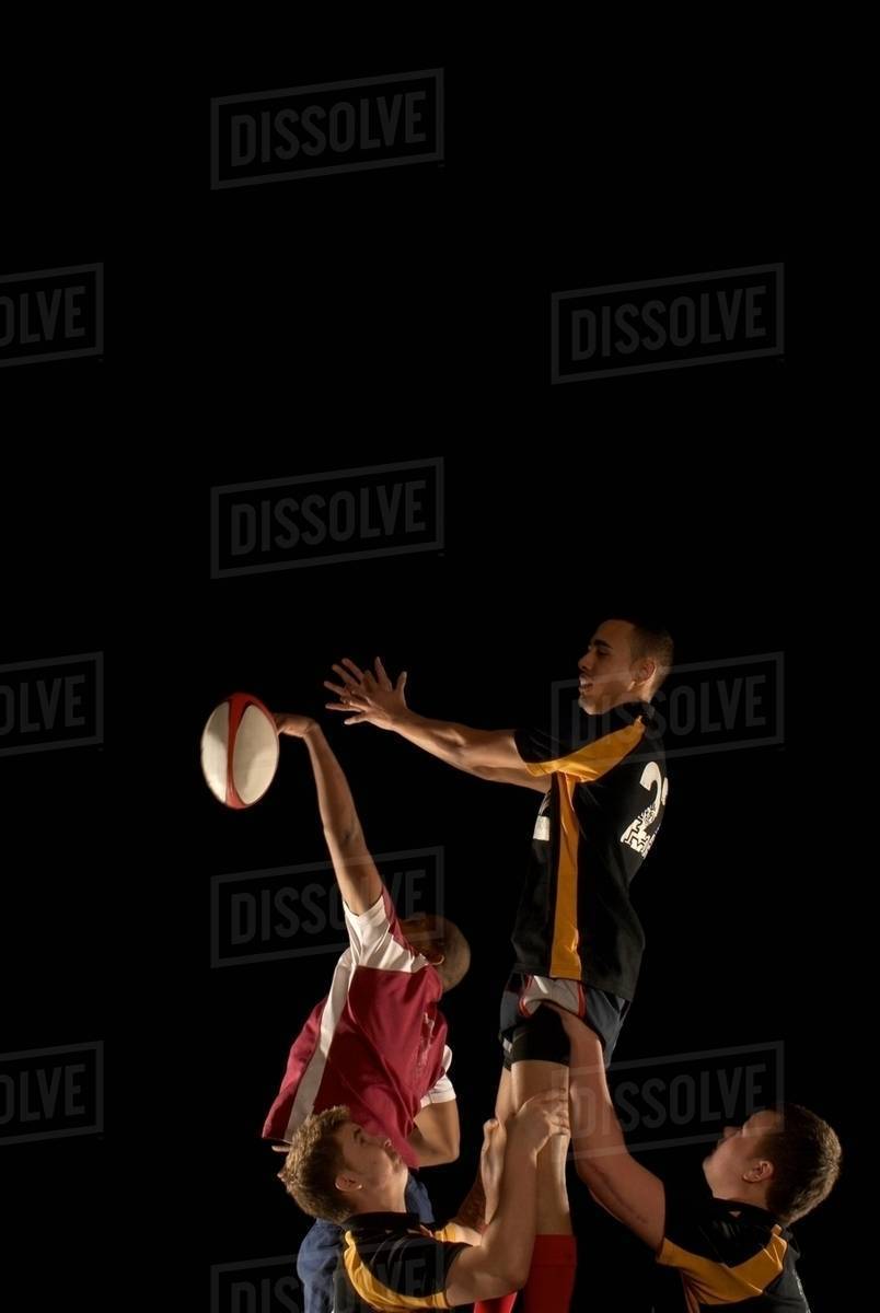 Rugby players competing for ball in air - Stock Photo - Dissolve