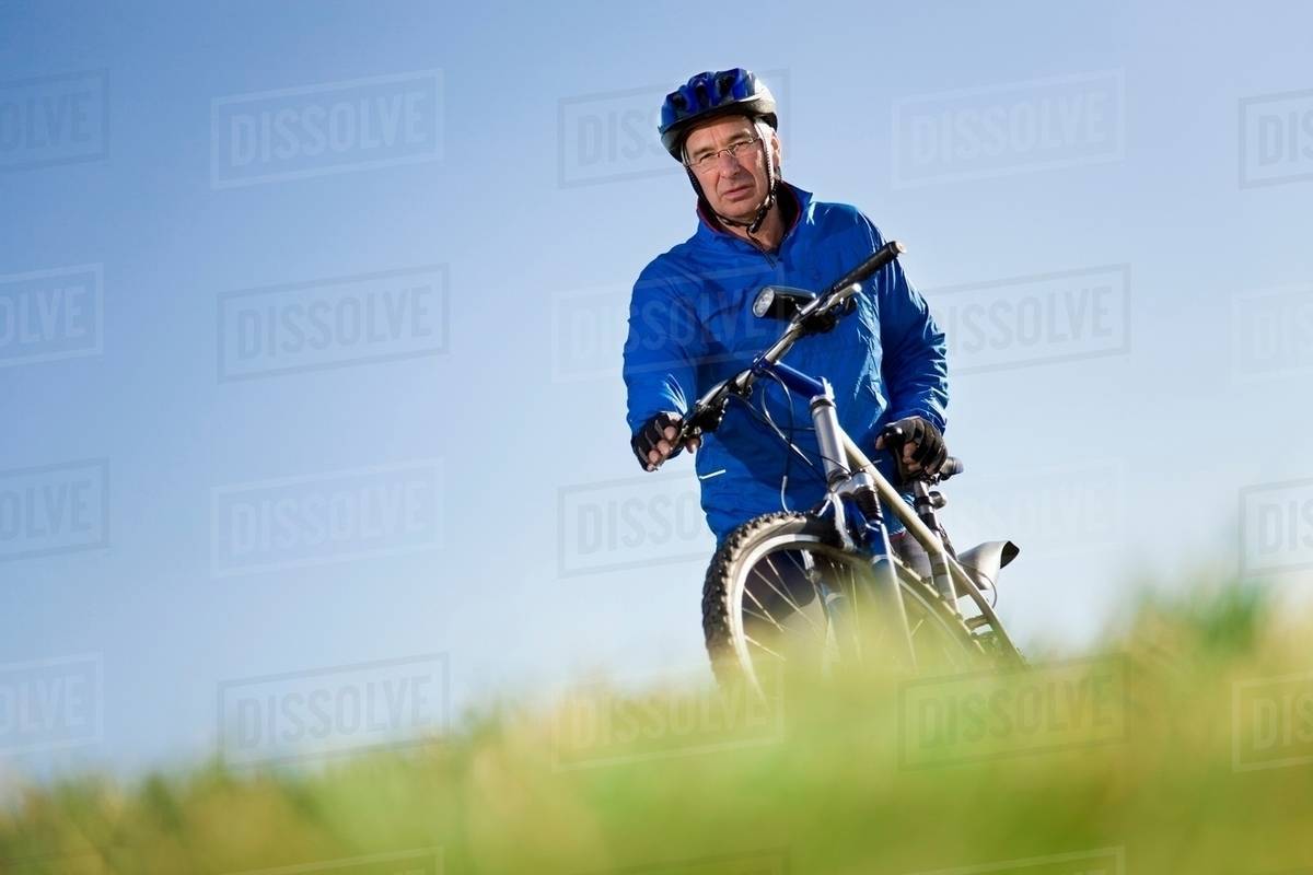 Senior man pushing mountain bike - Royalty-free Stock Photo | Dissolve