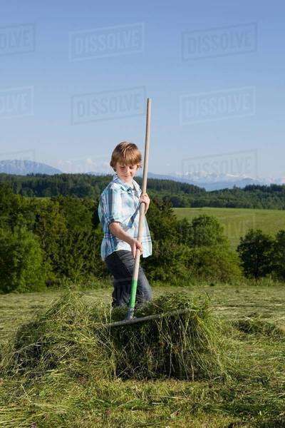 Boy raking the lawn on meadow - Royalty-free Stock Photo | Dissolve