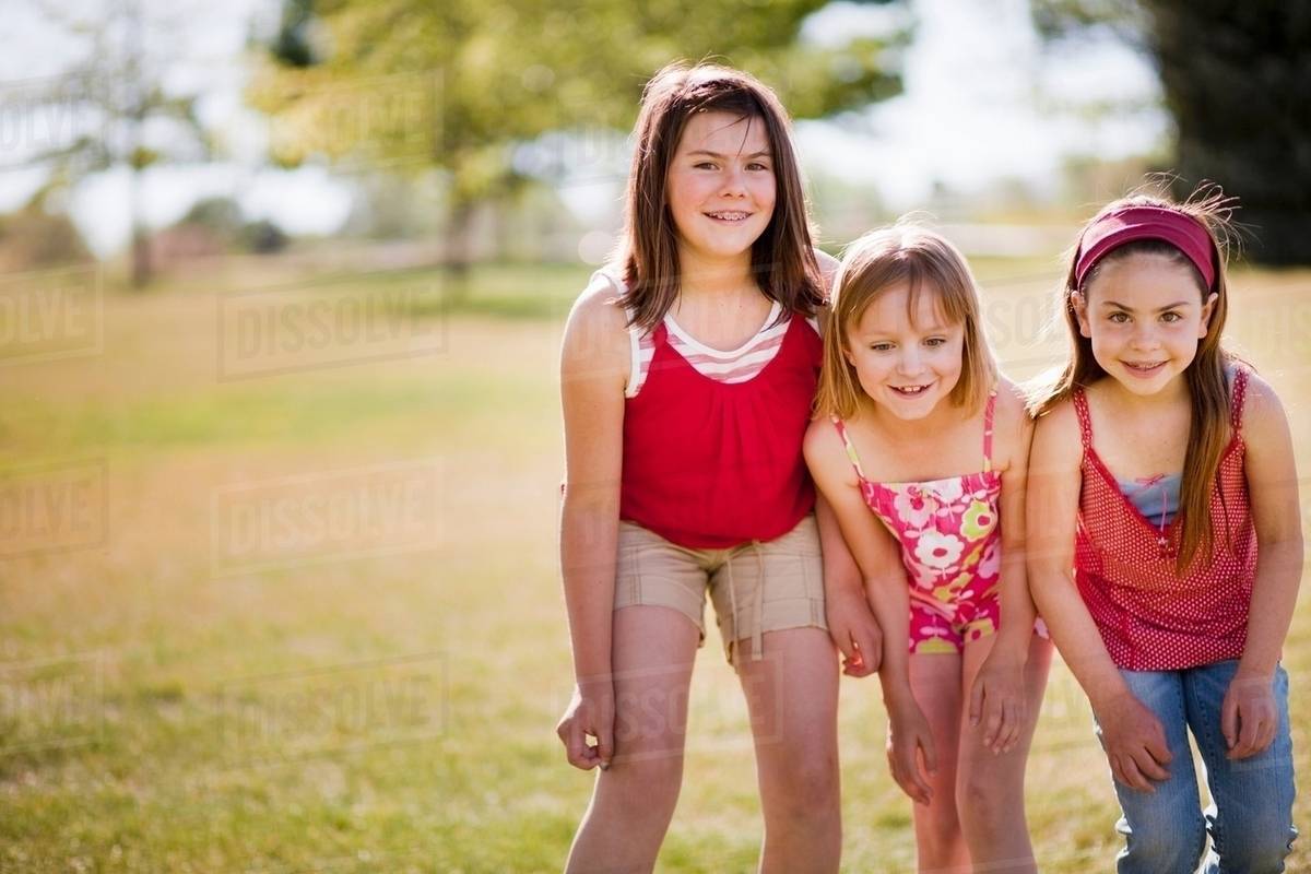 3 young girls standing in line laughing - Stock Photo - Dissolve