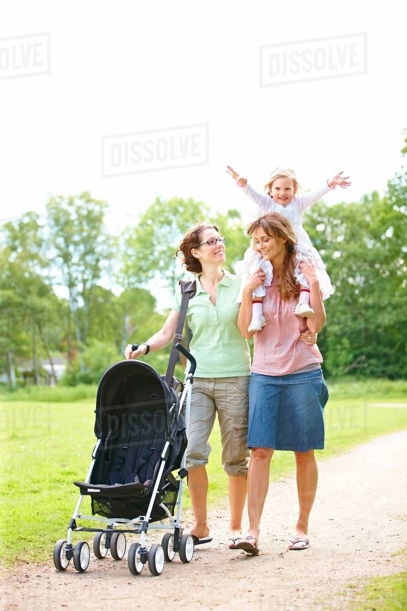 Two women with pram and girl walking - Royalty-free Stock Photo | Dissolve