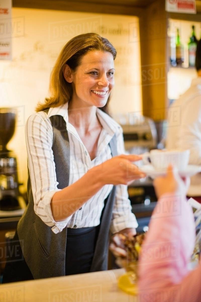 Woman serving coffee in cafÃ© - Royalty-free Stock Photo | Dissolve