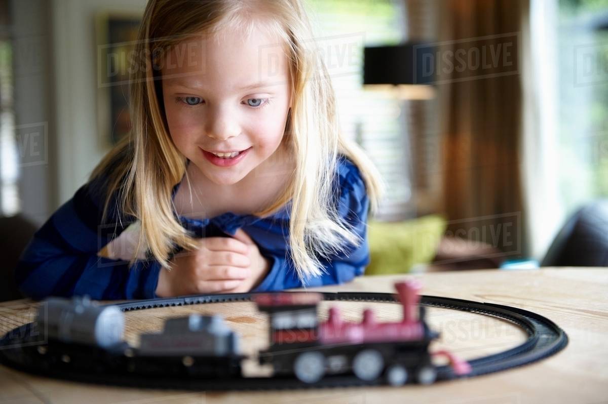 Girl playing with toy train - Stock Photo - Dissolve
