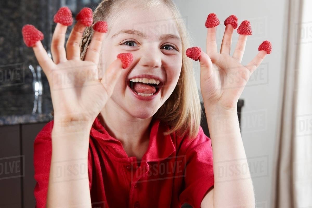 Girl with raspberries on fingers - Royalty-free Stock Photo | Dissolve
