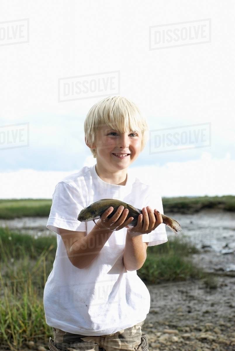 Boy holding fish up - Stock Photo - Dissolve