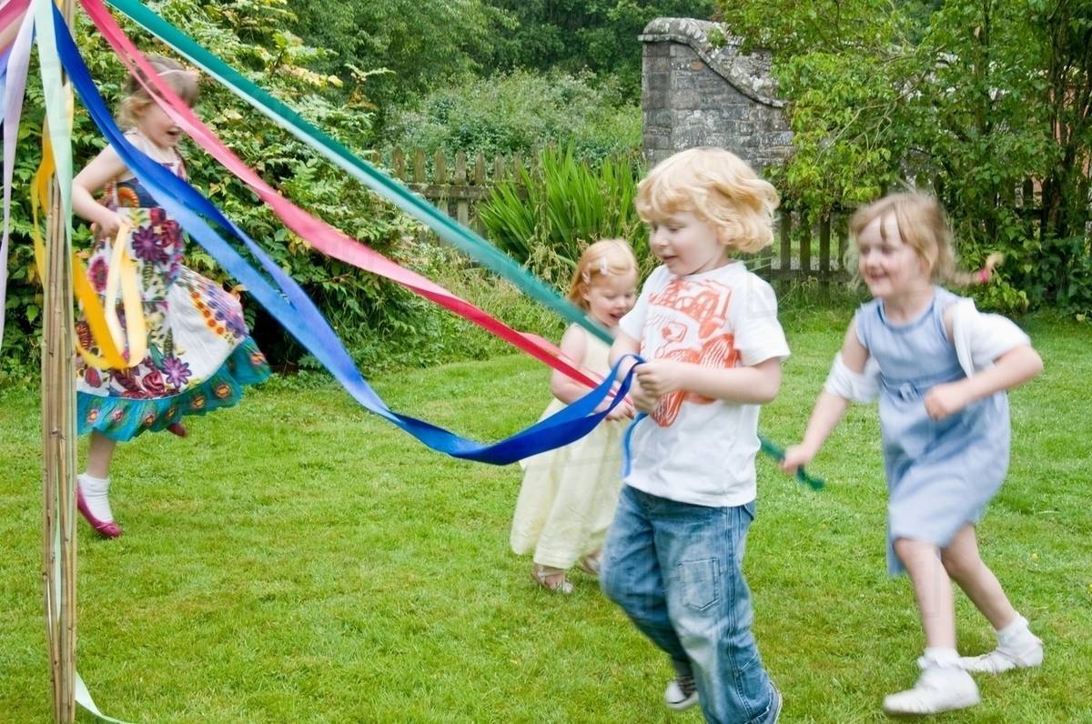 Children dancing round a maypole - Stock Photo - Dissolve