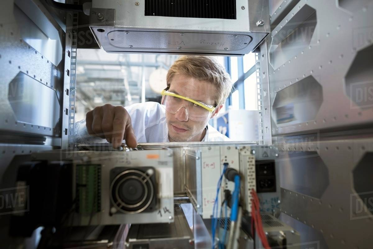 Factory technician inspecting machine electronics - Stock Photo - Dissolve