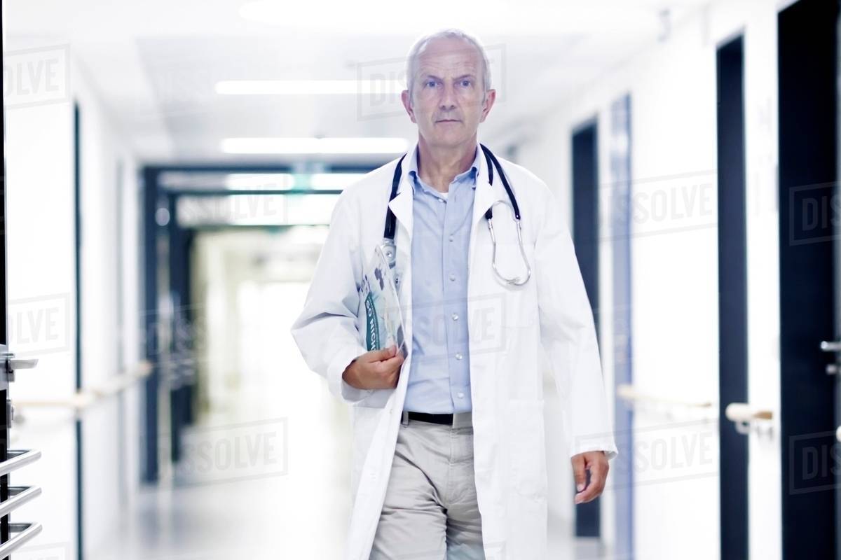 Male doctor walking along corridor - Royalty-free Stock Photo | Dissolve