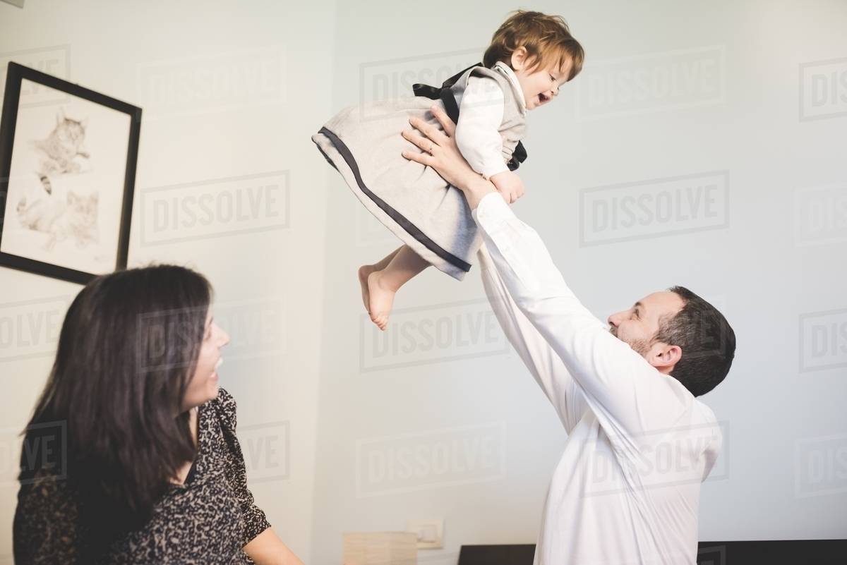 Mid adult man lifting up toddler daughter in living room - Royalty-free ...