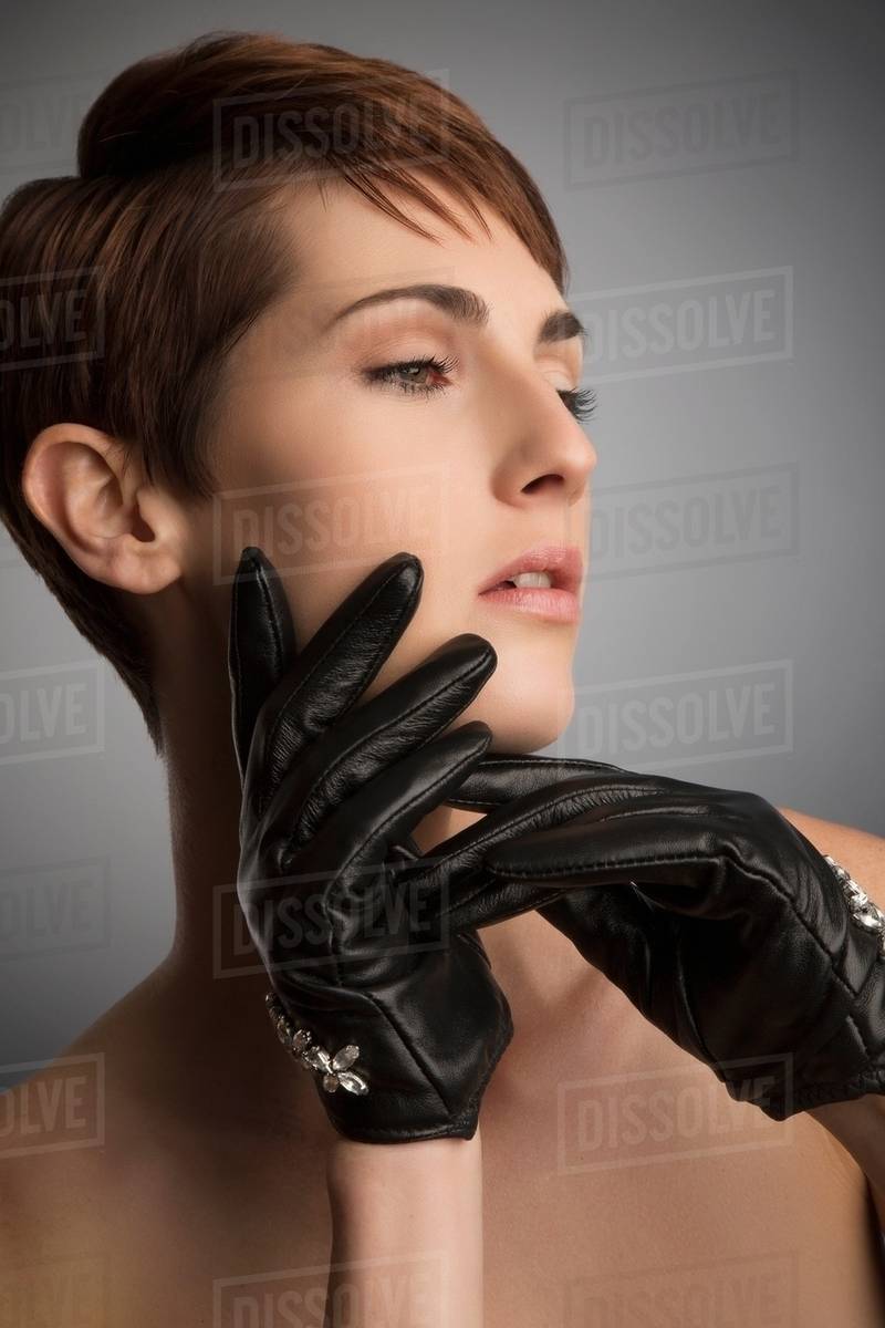 Studio portrait of woman with hand on her cheek wearing black leather ...