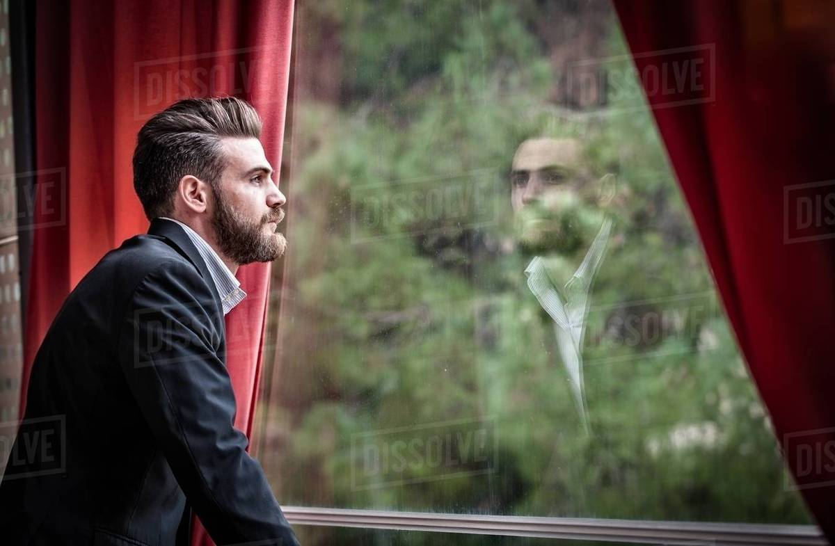 Side view of mid adult man wearing suit looking out of window - Stock ...