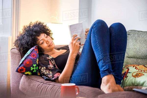 Mature woman reclining on sofa reading book - Royalty-free Stock Photo ...