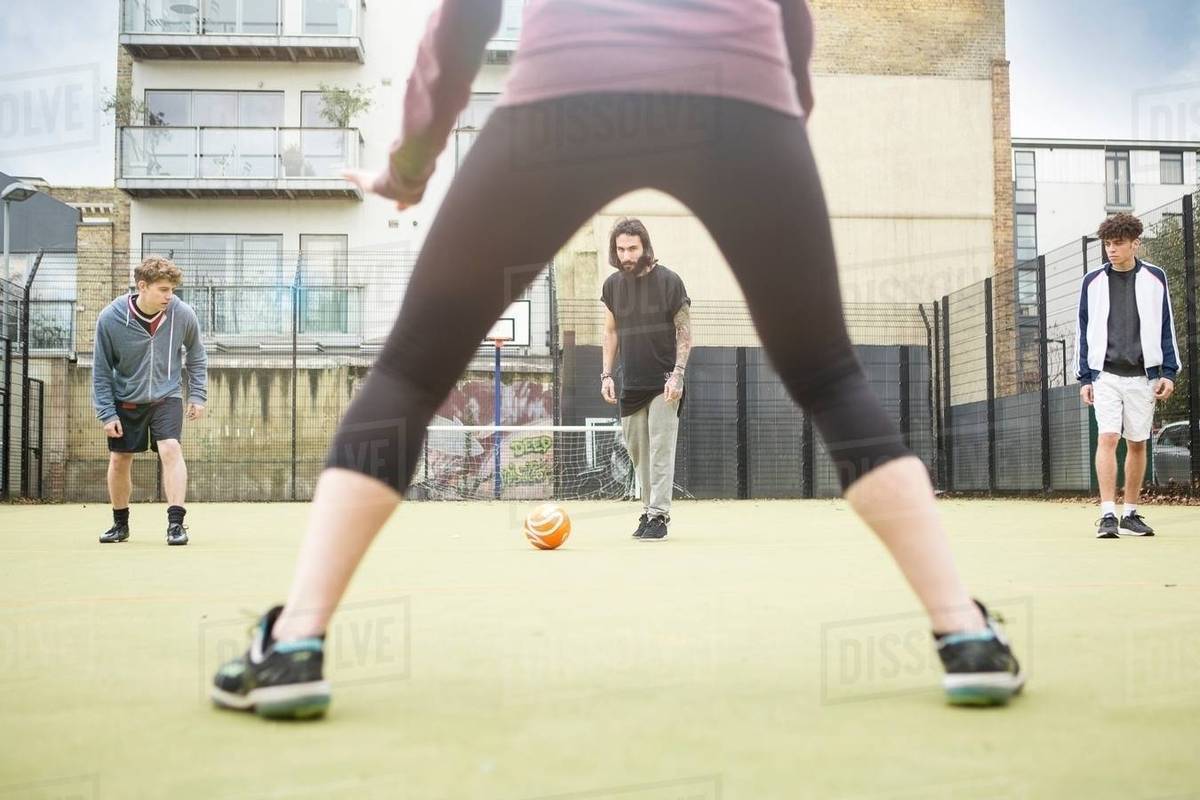 Group of adults playing football on urban football pitch - Royalty-free ...
