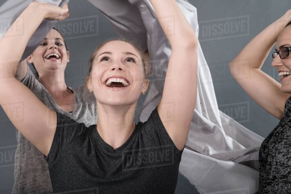 Young women holding cloth over head, grey background - Stock Photo ...