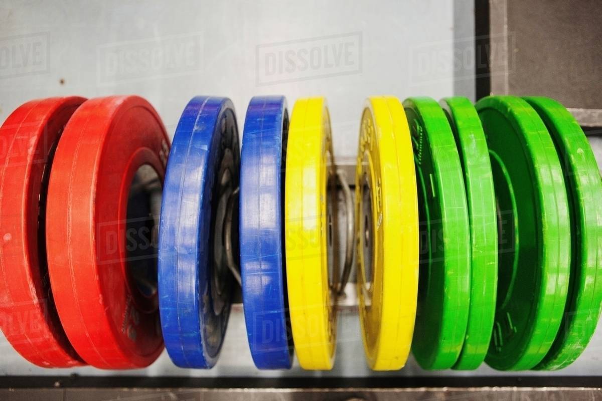 Brightly coloured barbell weights in a row - Stock Photo - Dissolve