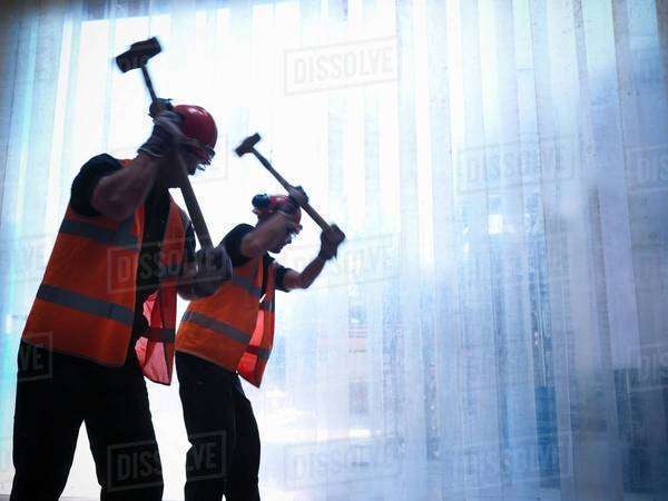 Silhouette of workers swinging hammers - Stock Photo - Dissolve