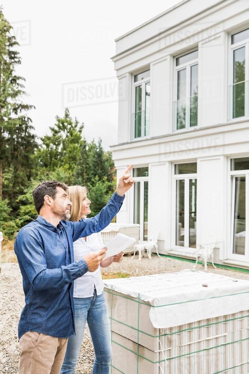 Architect showing homeowner plans for house exterior, looking up ...
