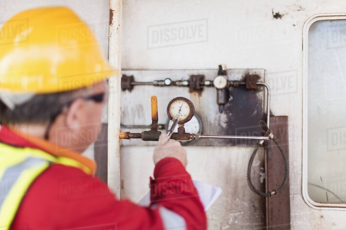 Worker checking gauge on oil rig - Royalty-free Stock Photo | Dissolve