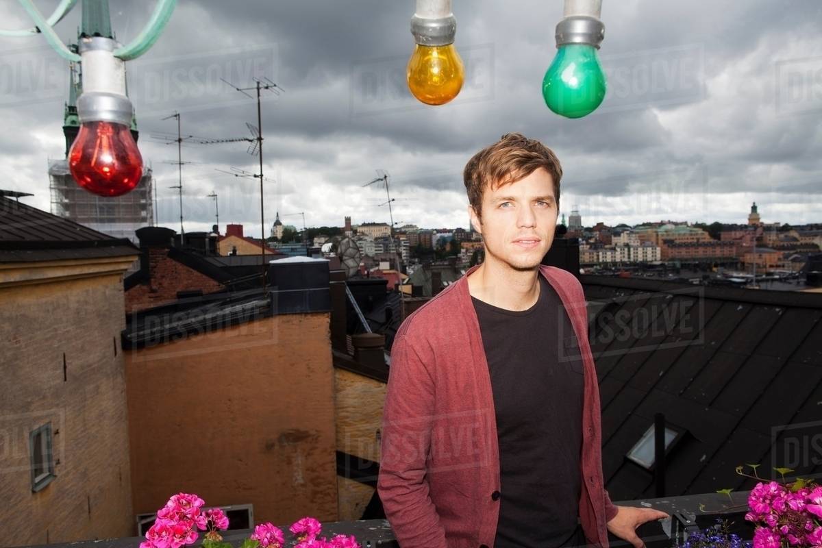 Man standing on balcony overlooking city - Stock Photo - Dissolve