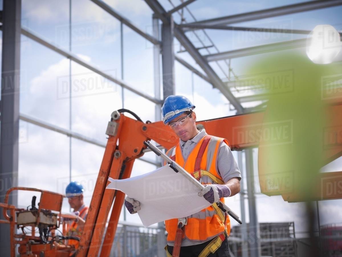 Construction worker reading blueprints - Stock Photo - Dissolve