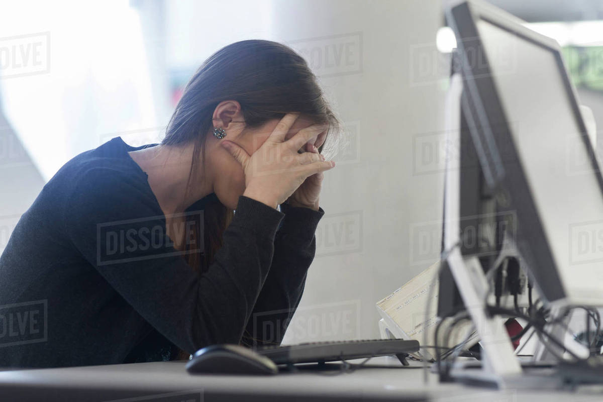 Side view of woman sitting at computer head in hands - Royalty-free ...