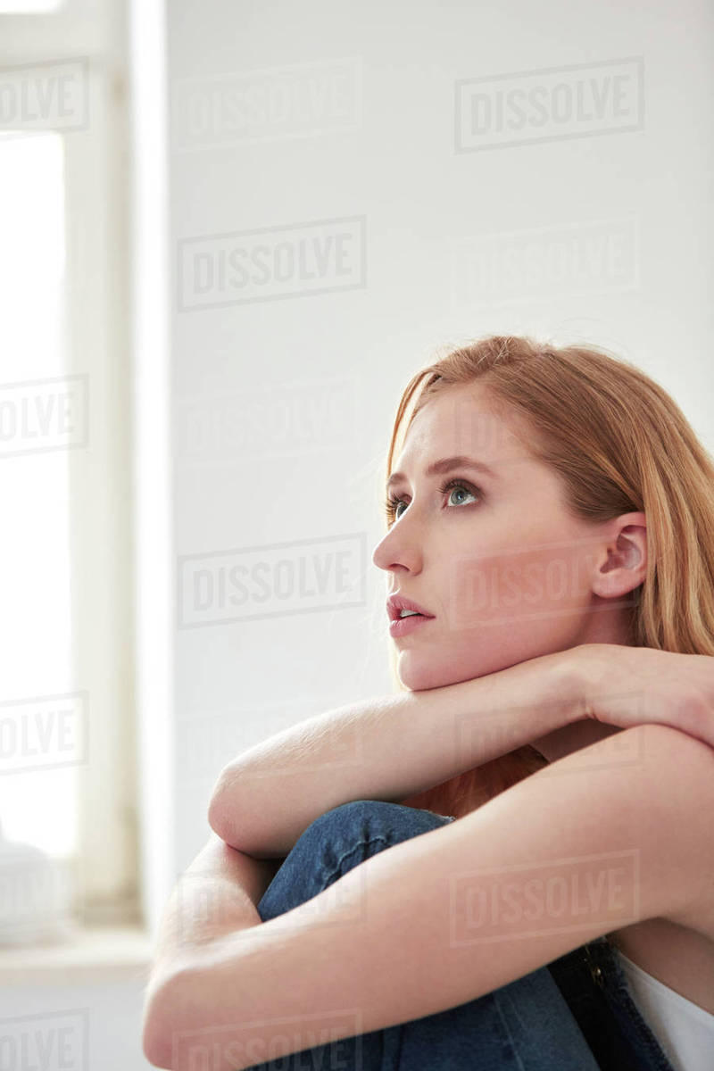 Young woman hugging knees and looking up - Royalty-free Stock Photo ...