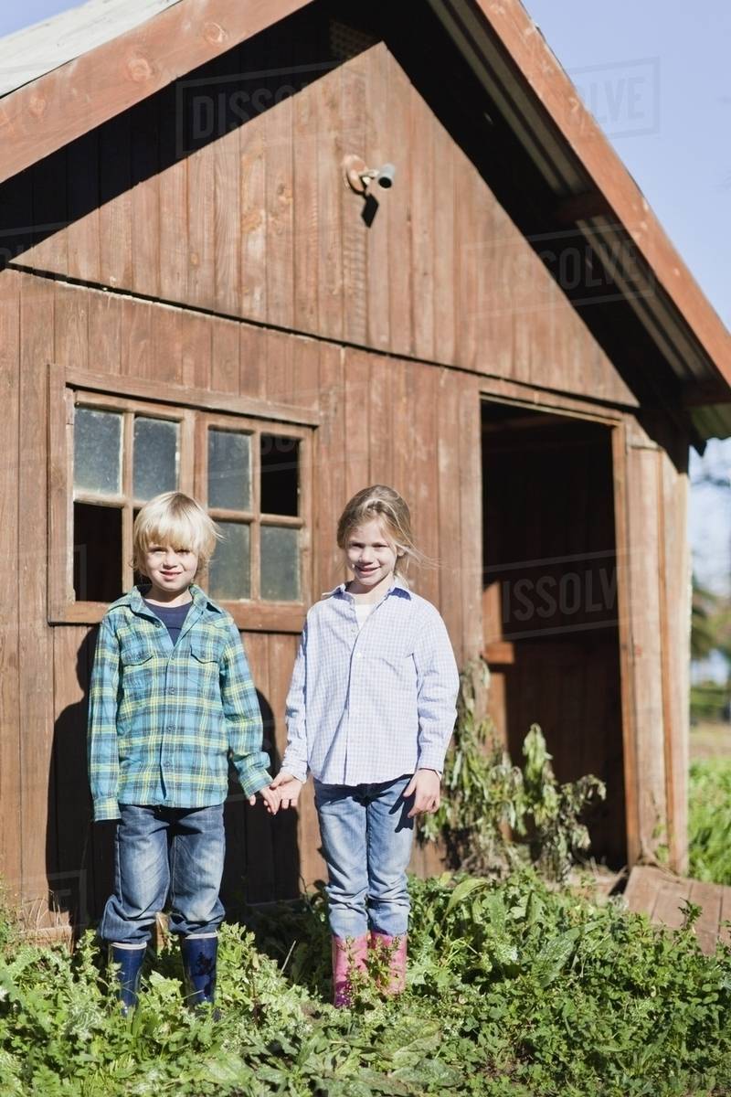 Children holding hands outside shed - Royalty-free Stock Photo | Dissolve