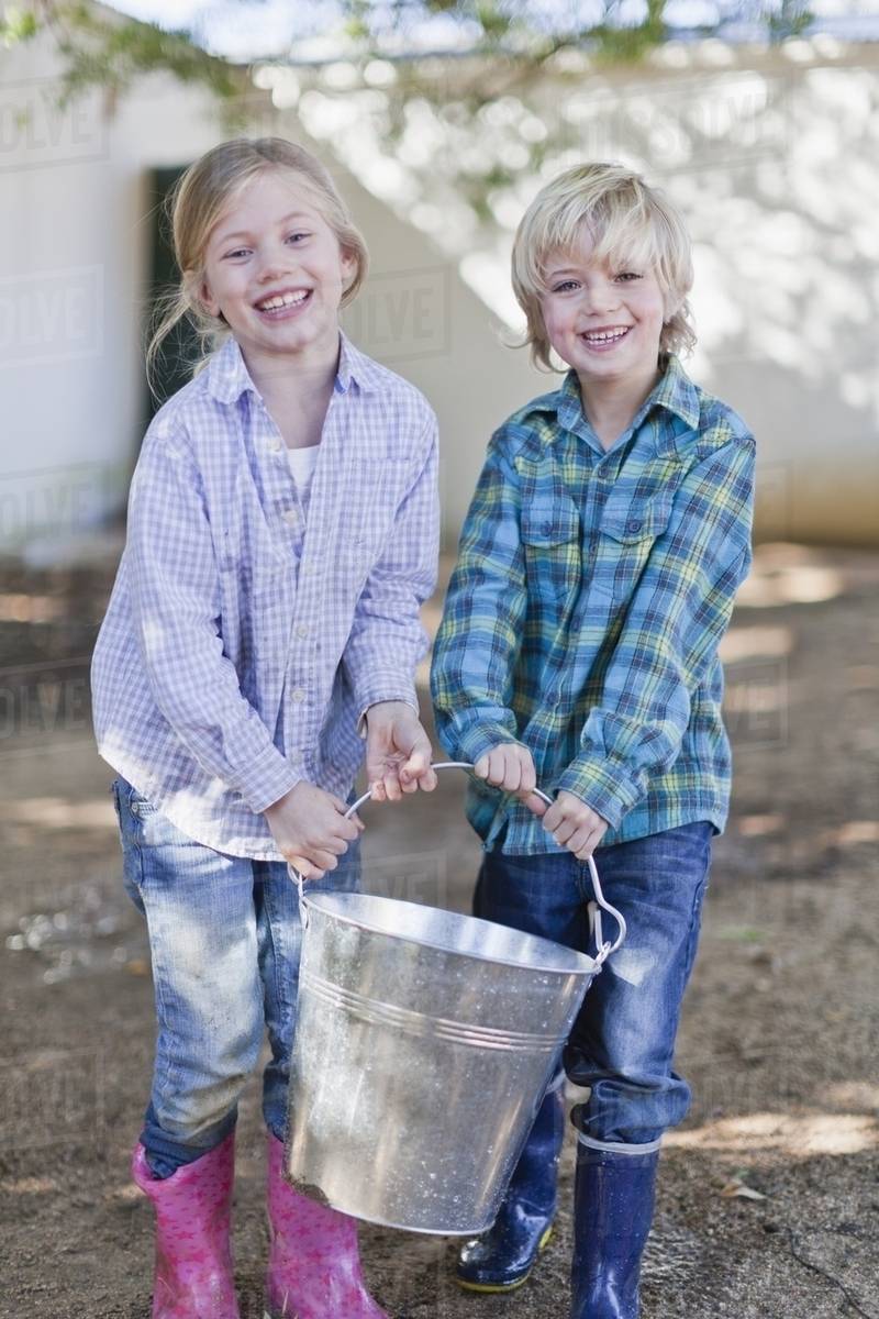 Children carrying heavy pail outdoors - Royalty-free Stock Photo | Dissolve