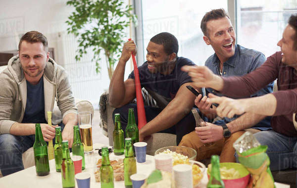 Group of men in lounge sitting around table with beer bottles and ...
