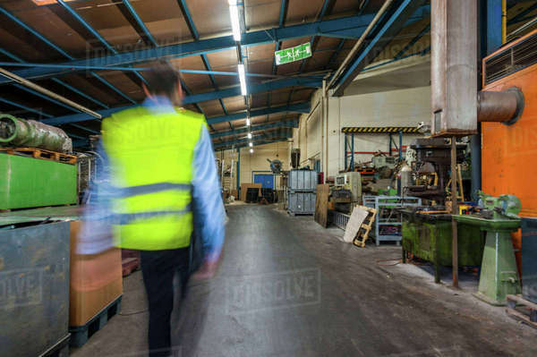 Rear view of worker walking in rubber manufacturing plant, blurred ...