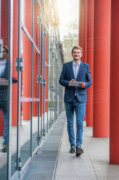 Full length front view of man wearing jeans and suit jacket holding ...