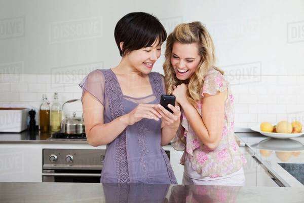 Laughing women using cell phone - Stock Photo - Dissolve