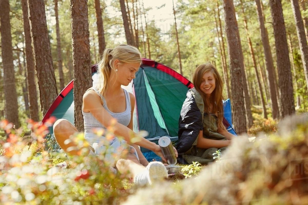 Women setting up campsite in forest - Royalty-free Stock Photo | Dissolve