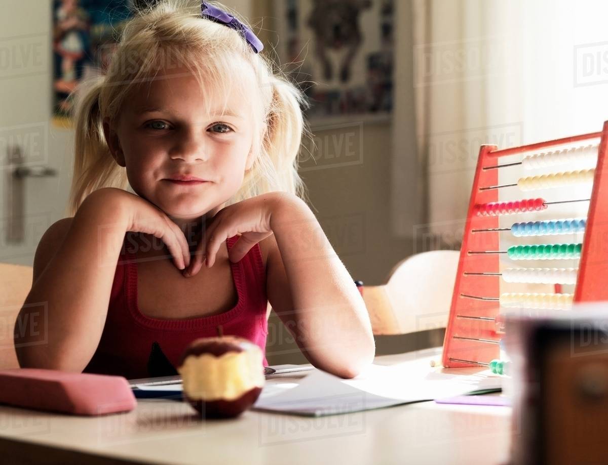 Girl sitting at desk with apple - Royalty-free Stock Photo | Dissolve