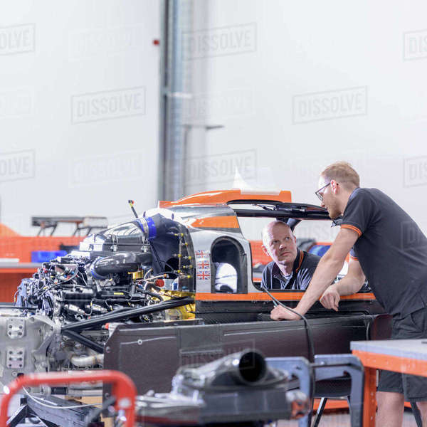 Engineers working in racing car during assembly in racing car factory ...