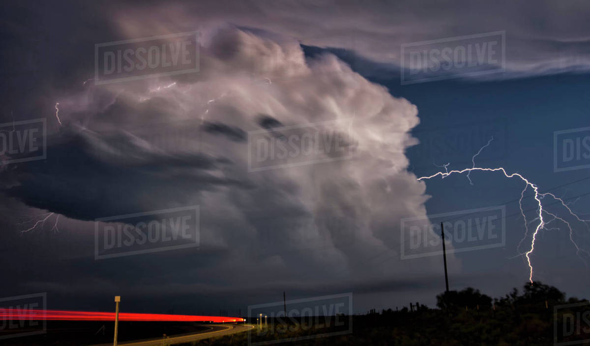 Vehicle light trails and lightning bolt arcing laterally from storm ...