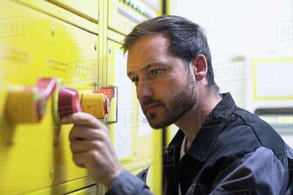 Man adjusting leaver on control panel - Royalty-free Stock Photo | Dissolve