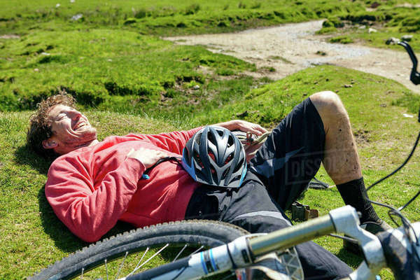 Cyclist lying down on grass by bicycle - Royalty-free Stock Photo ...